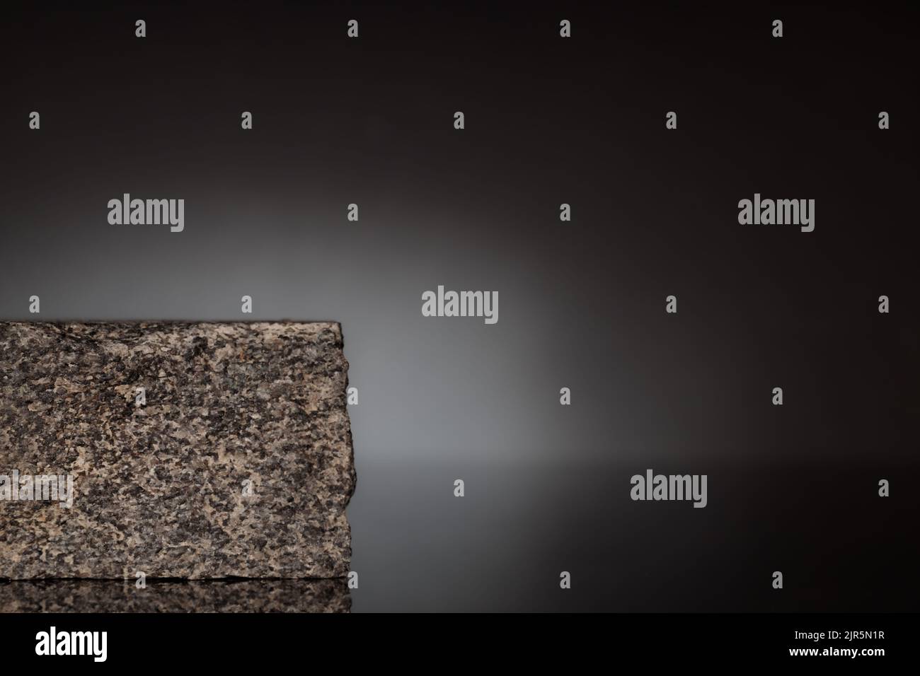 Minimalist, raw granite platform on a black background. Product ...