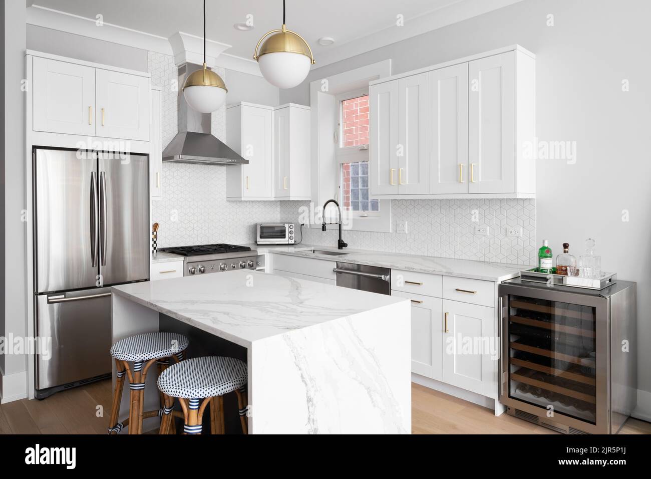 A beautiful white kitchen with bar stools sitting at a waterfall ...