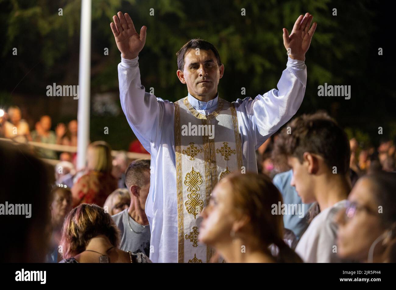 A priest praying over young people at the conclusion of the Mladifest ...