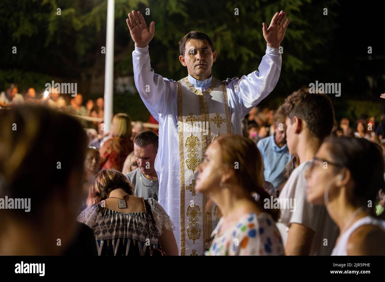 A priest praying over young people at the conclusion of the Mladifest ...