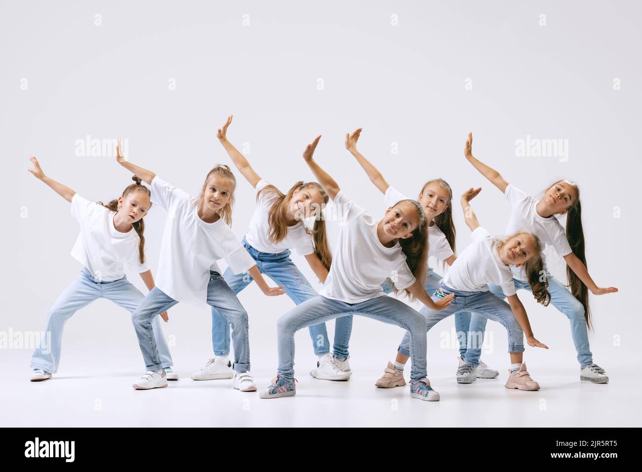 Dance group of happy, active little girls in jeans and t-shirts dancing ...