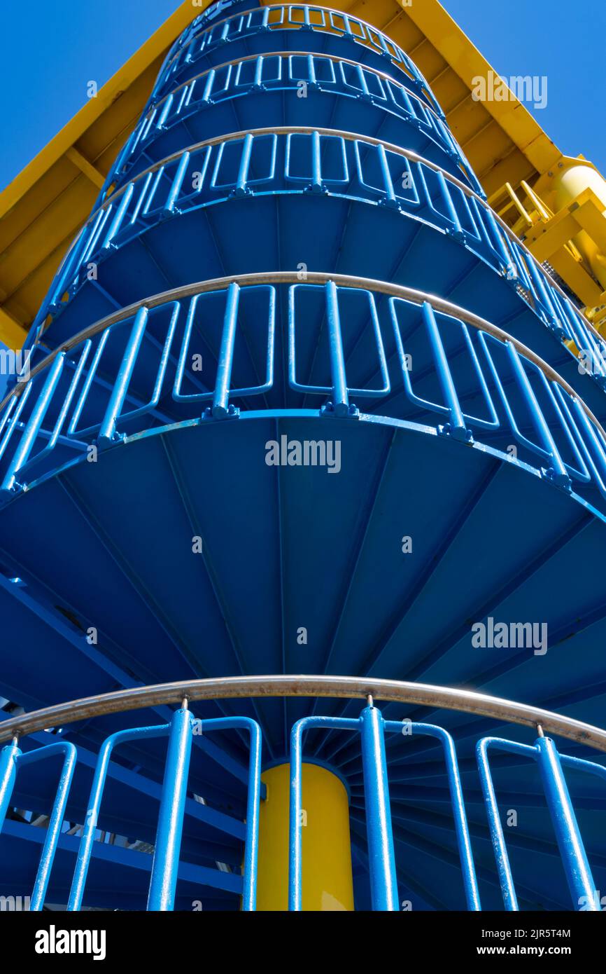 Low angle view of a blue spiral staircase with a yellow platform on top ...