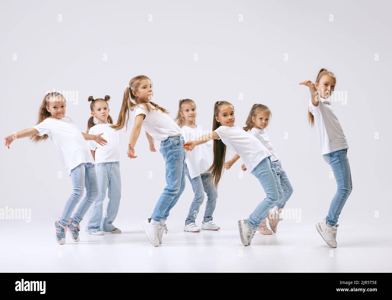 Dance group of happy, active little girls in jeans and t-shirts dancing ...