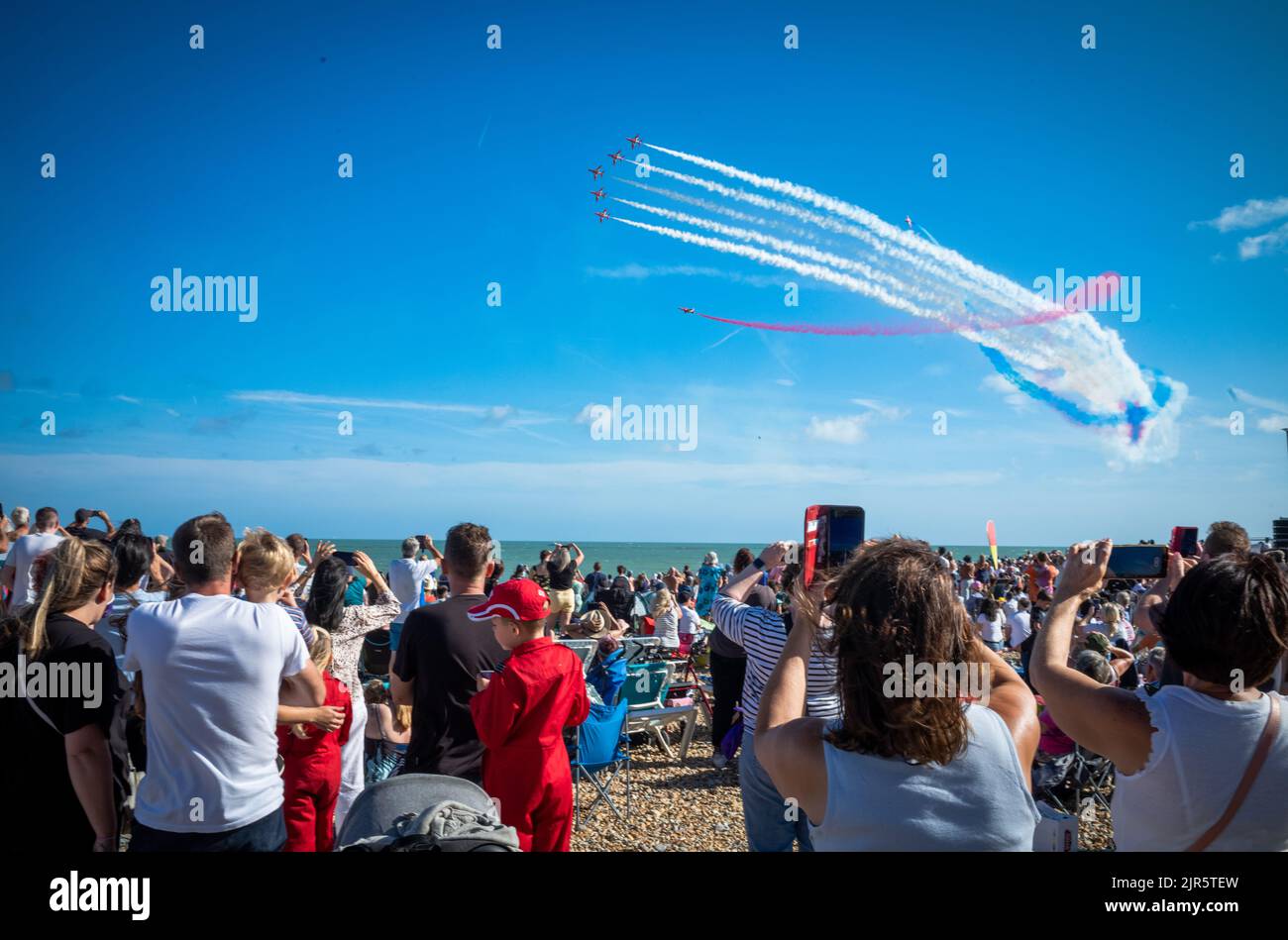 People watch the RAF Red Arrows aerobatic display team from the beach ...