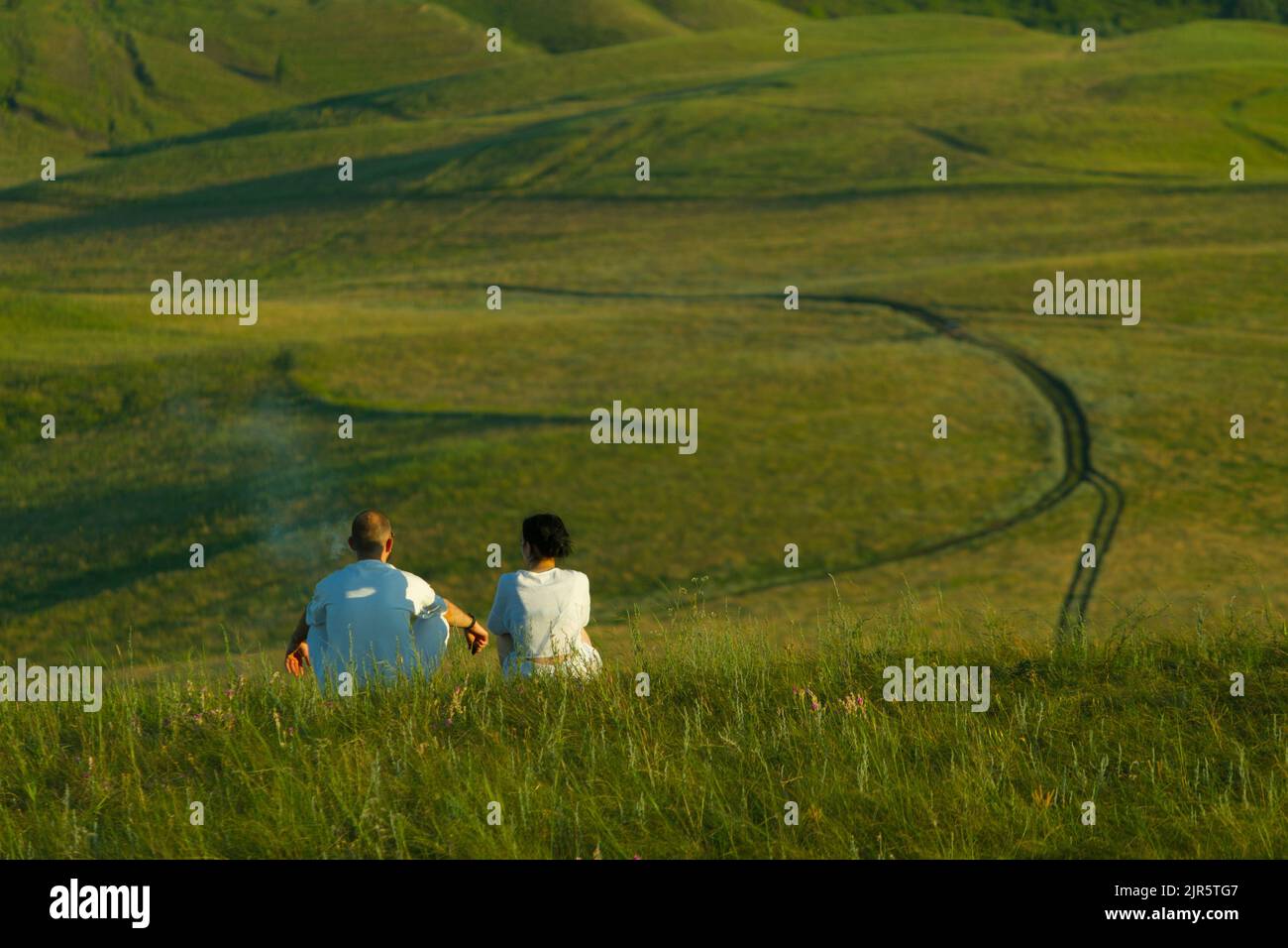 Couple sit on the grass and watch beautiful landscape Stock Photo - Alamy