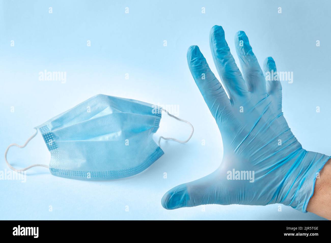 Medical mask and hand in latex protective glove with stop gesture. The ...