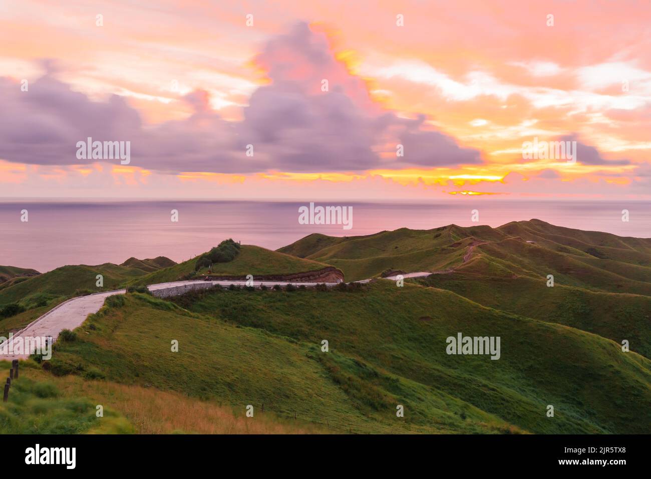 The walkway on the green hills under the pink sunset sky in Batanes ...