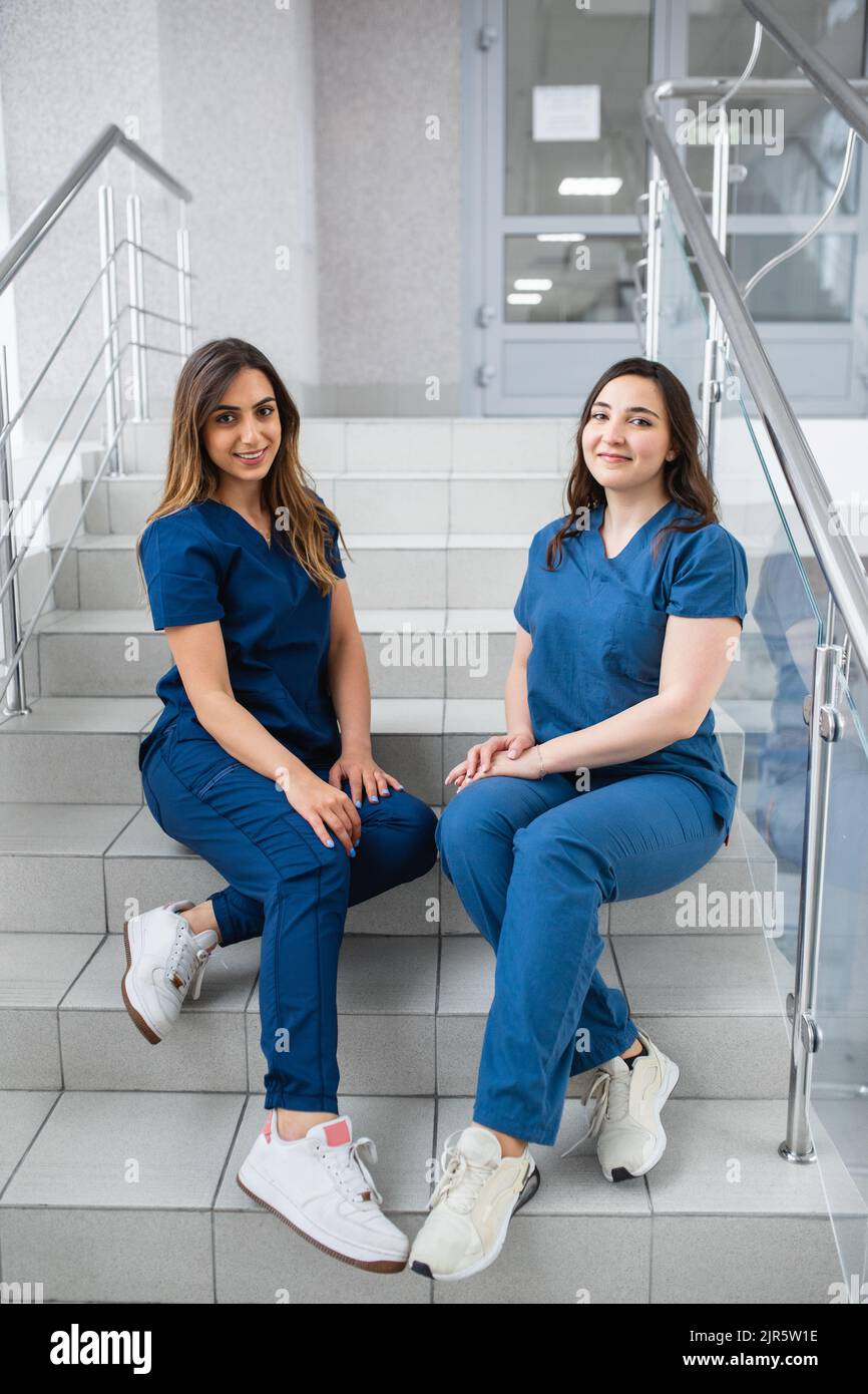 Two girls in surgical suits, on the stairs of the medical university. A ...