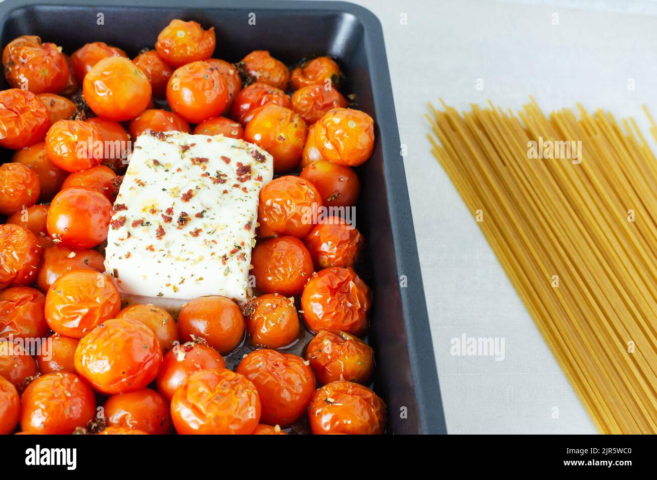 The process of making feta pasta. Baked cheese and tomatoes with herbs ...