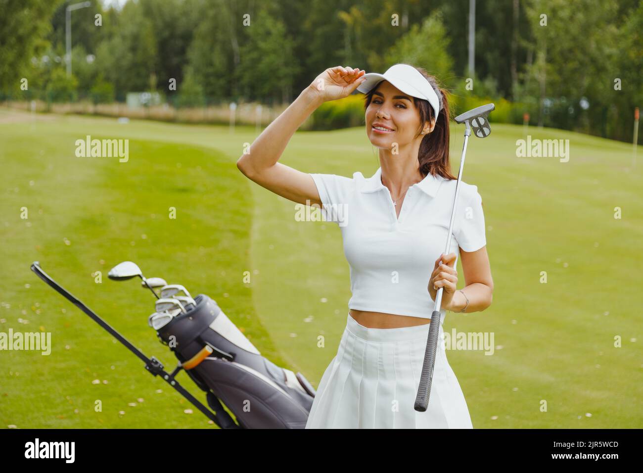 Smiling golfer woman with golf club outdoors on court. Active healthy ...
