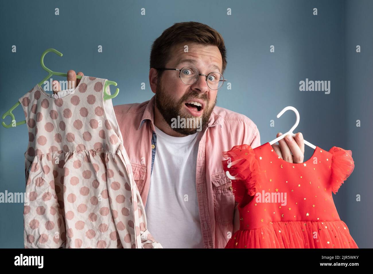 Father holds two children dresses in hands and looks inquiringly ...