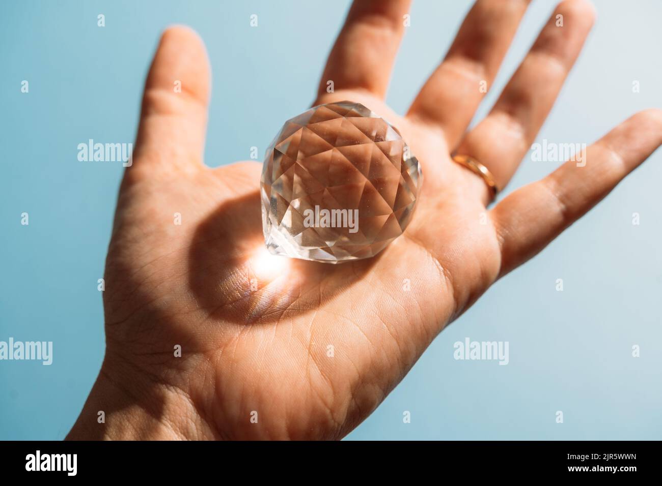Close up hand with crystal on blue background with sun light Stock ...