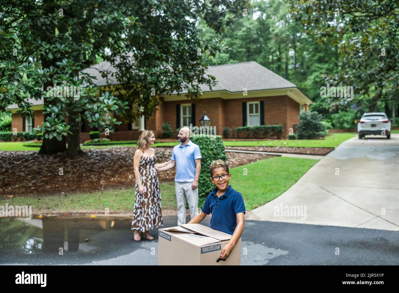 A little boy holding a moving box ready to move into his new house ...