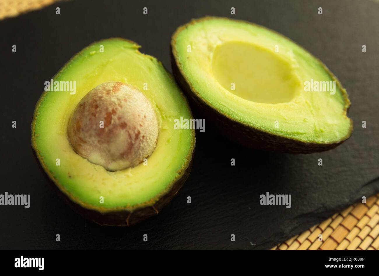ripe halved avocado with bone on black stone board Stock Photo - Alamy