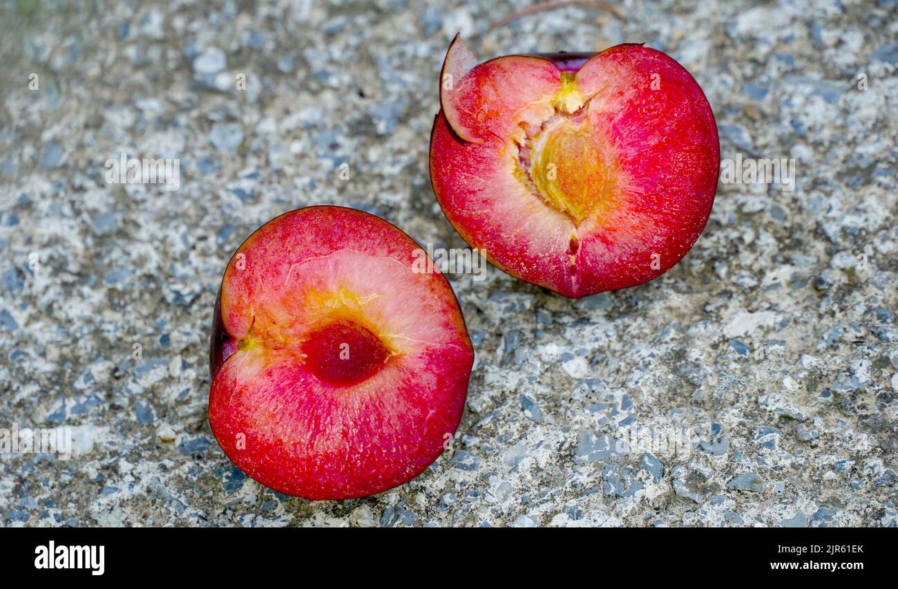 Juicy red Plum fruits with cut in half on concrete background Stock ...