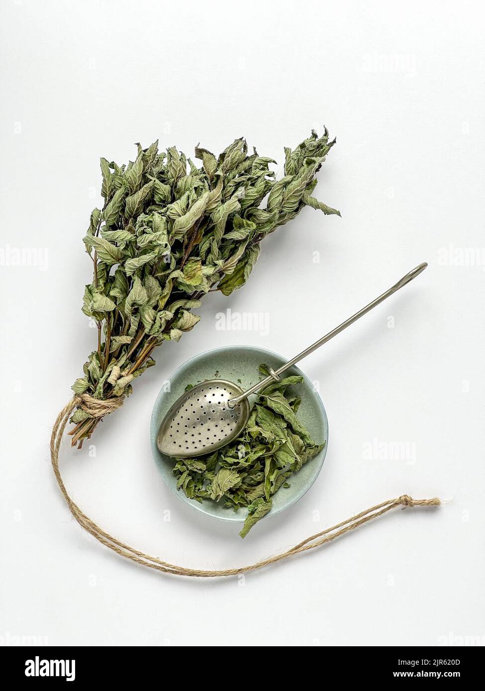 Dried mint leaves in green ceramic bowl on white background. Herbs for ...