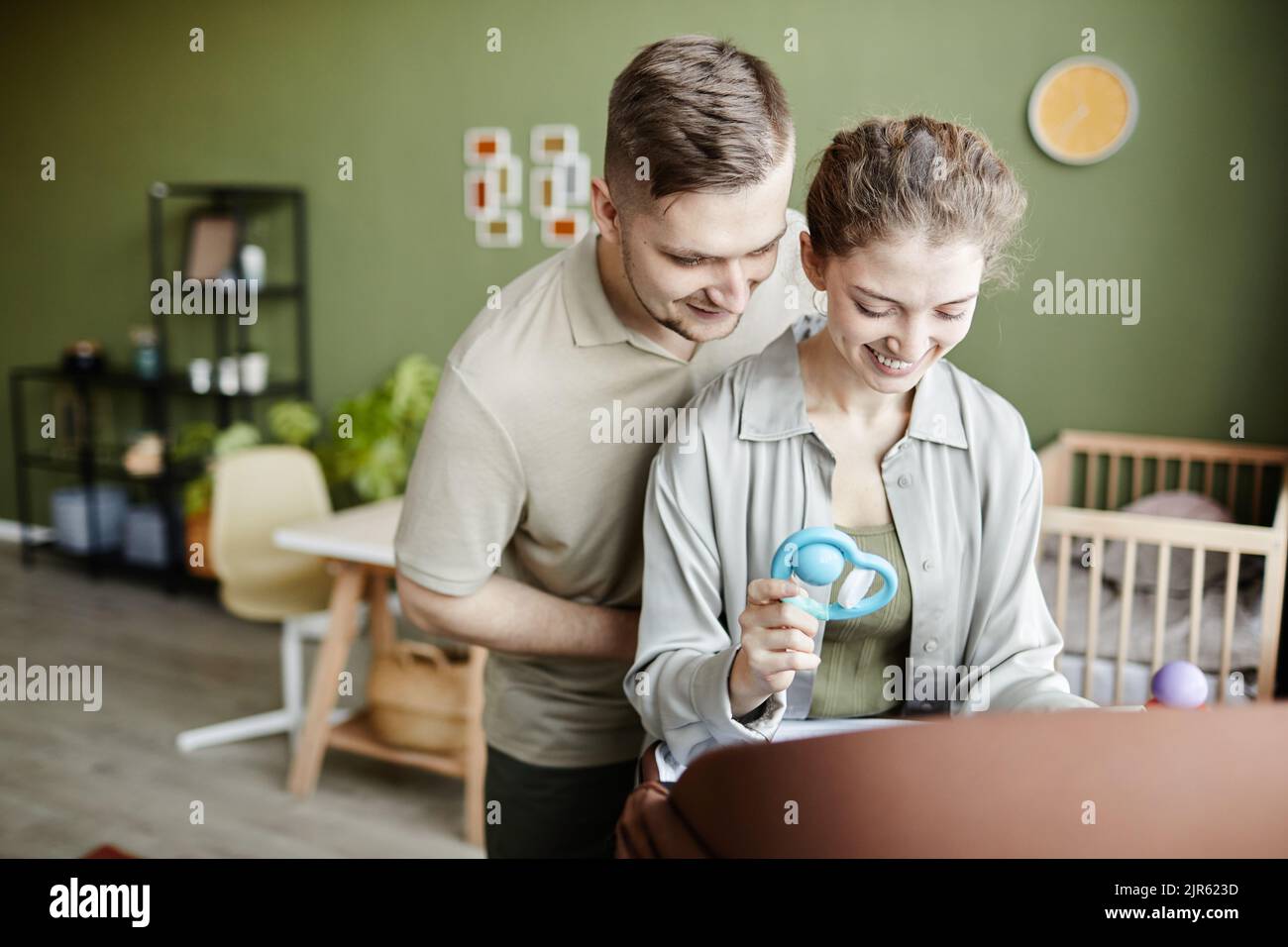 Happy young parents playing with their baby in cradle and enjoying ...