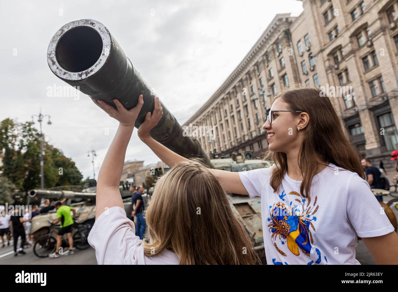 Girls touch the barrel of the tank with their hands. An exhibition of ...