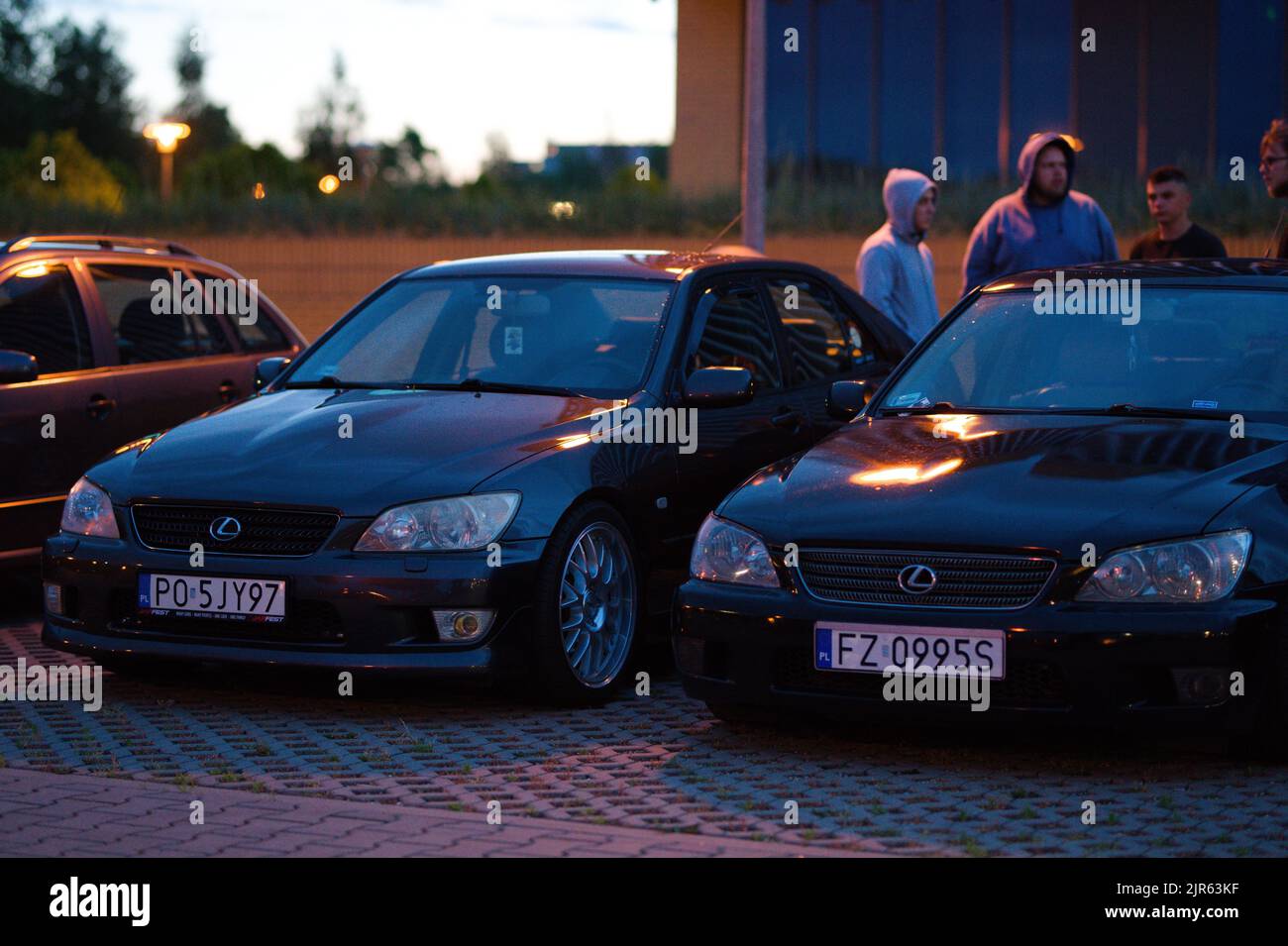 A Car meet in the evening front of two Lexus IS300s with people in the ...