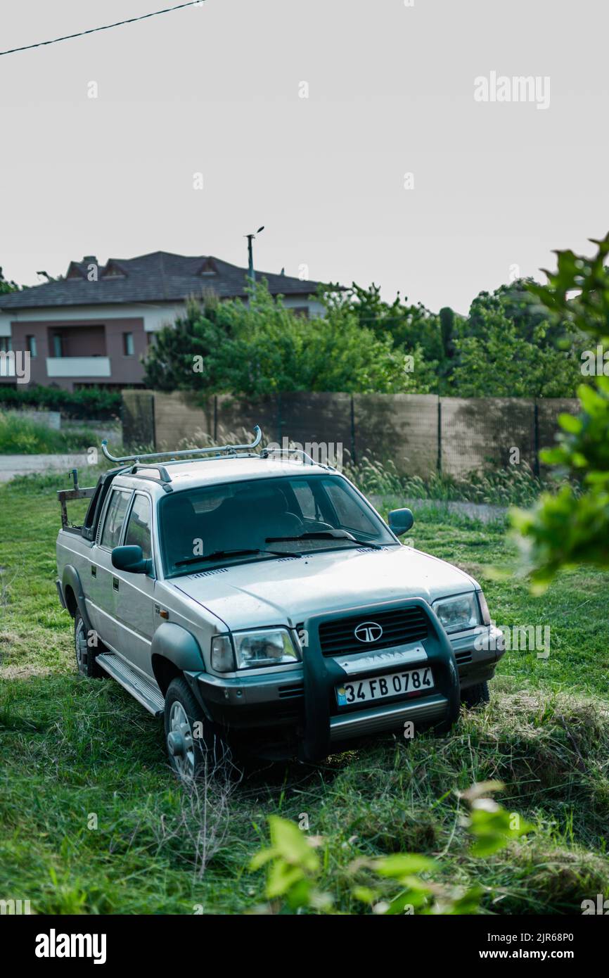 A vertical shot of a pick-up car standing in the greenery in a rural ...