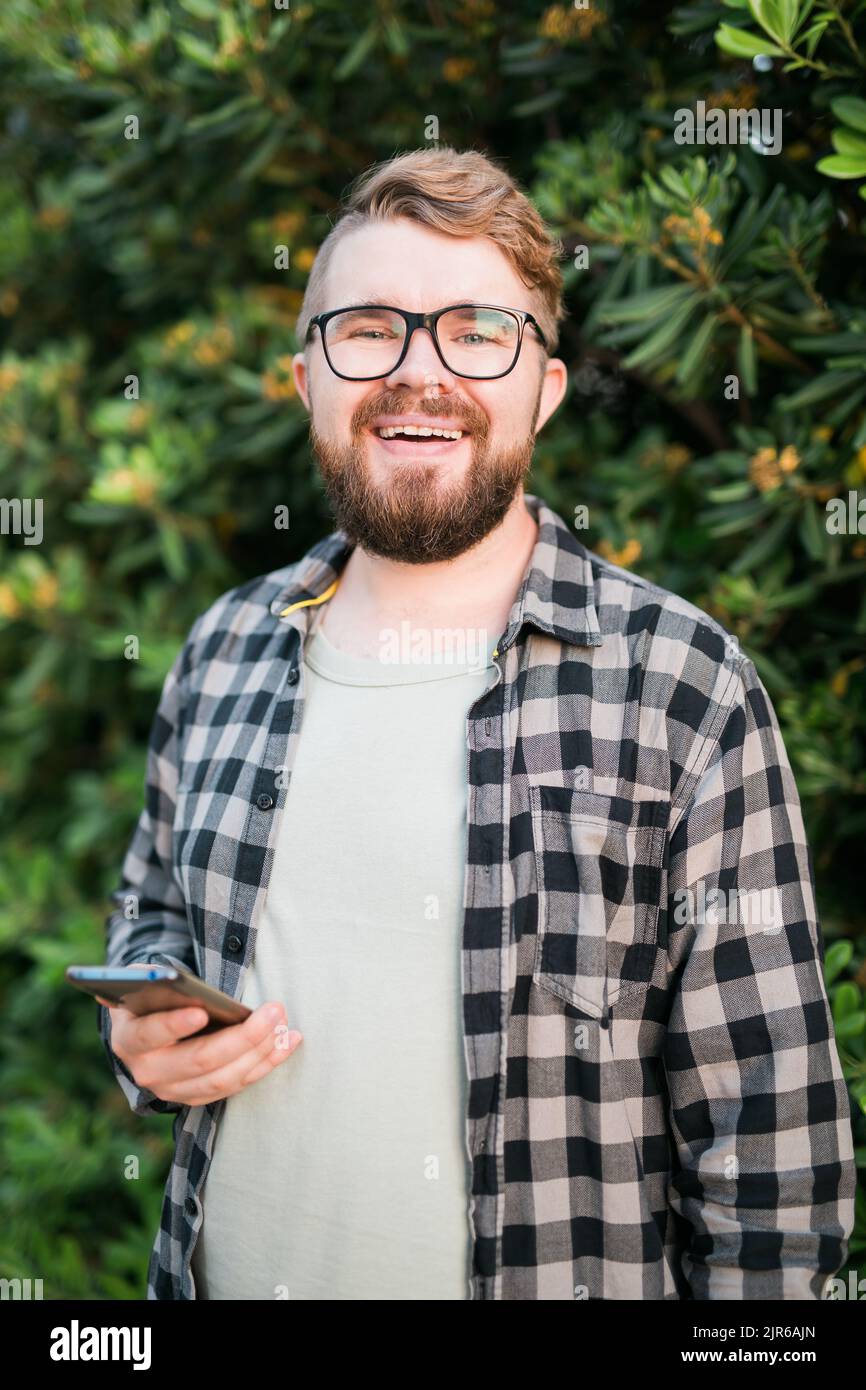 Portrait of attractive cheerful guy using smartphone for scrolling on ...