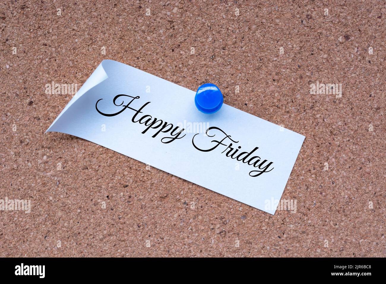 Happy Friday word on white stick note and pinned to a cork notice board ...