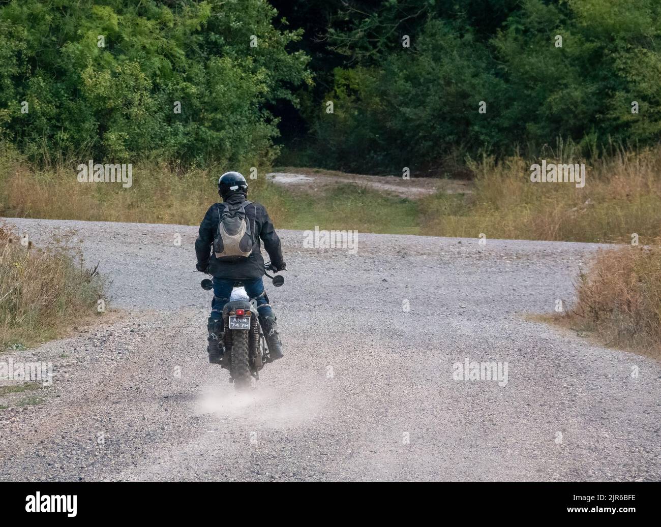a motor cyclist (biker) riding their off-road motorbike along a dusty ...