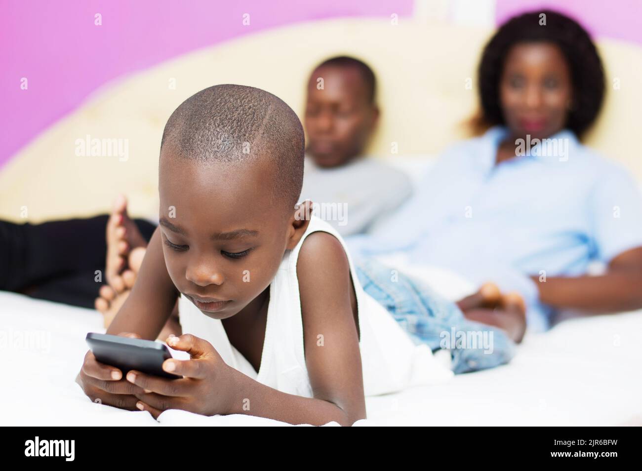 A child plays with the mobile phone of his parents who are watching in ...