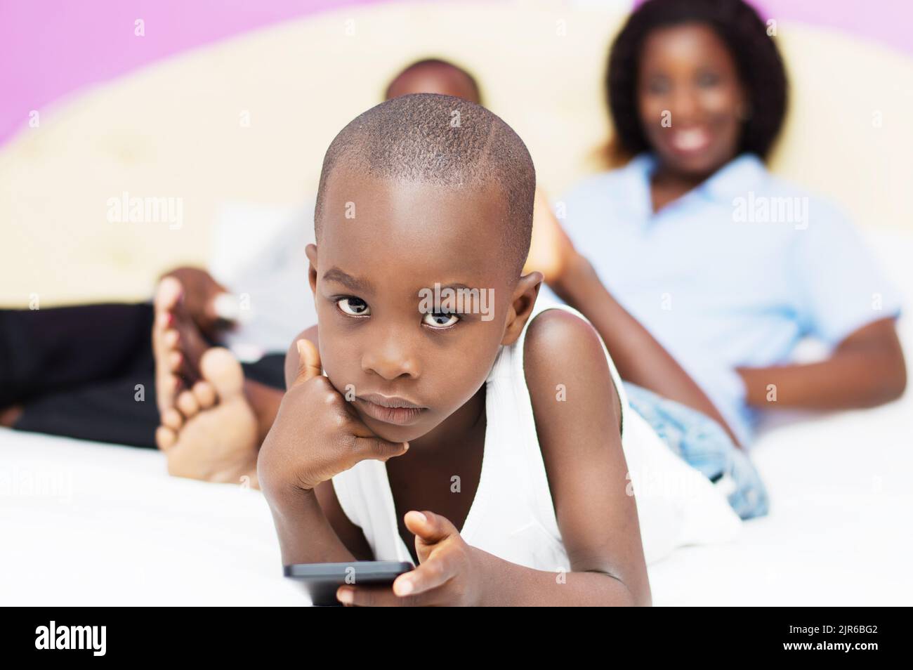 A child plays with the mobile phone of his parents who are watching in ...