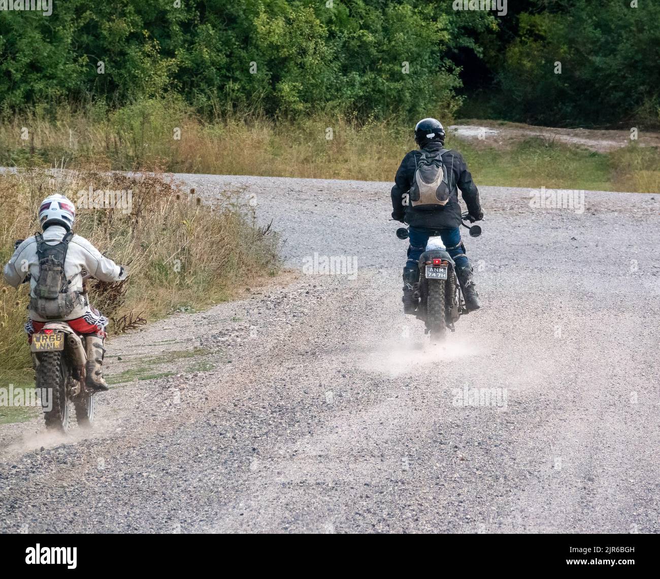 two motor cyclists (bikers) riding their off-road motorbikes along a ...