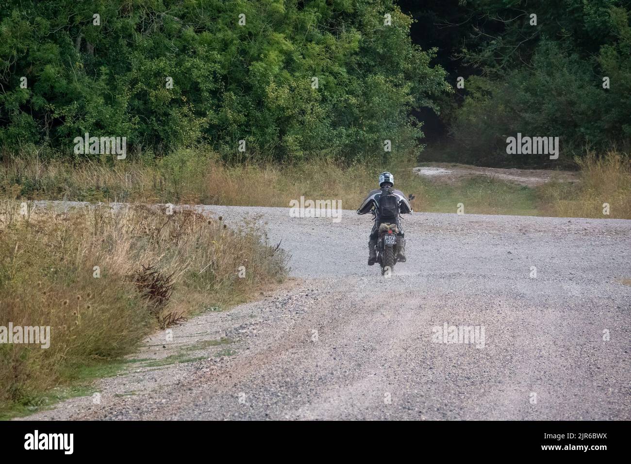 a motor cyclist (biker) riding their off-road motorbike along a dusty ...