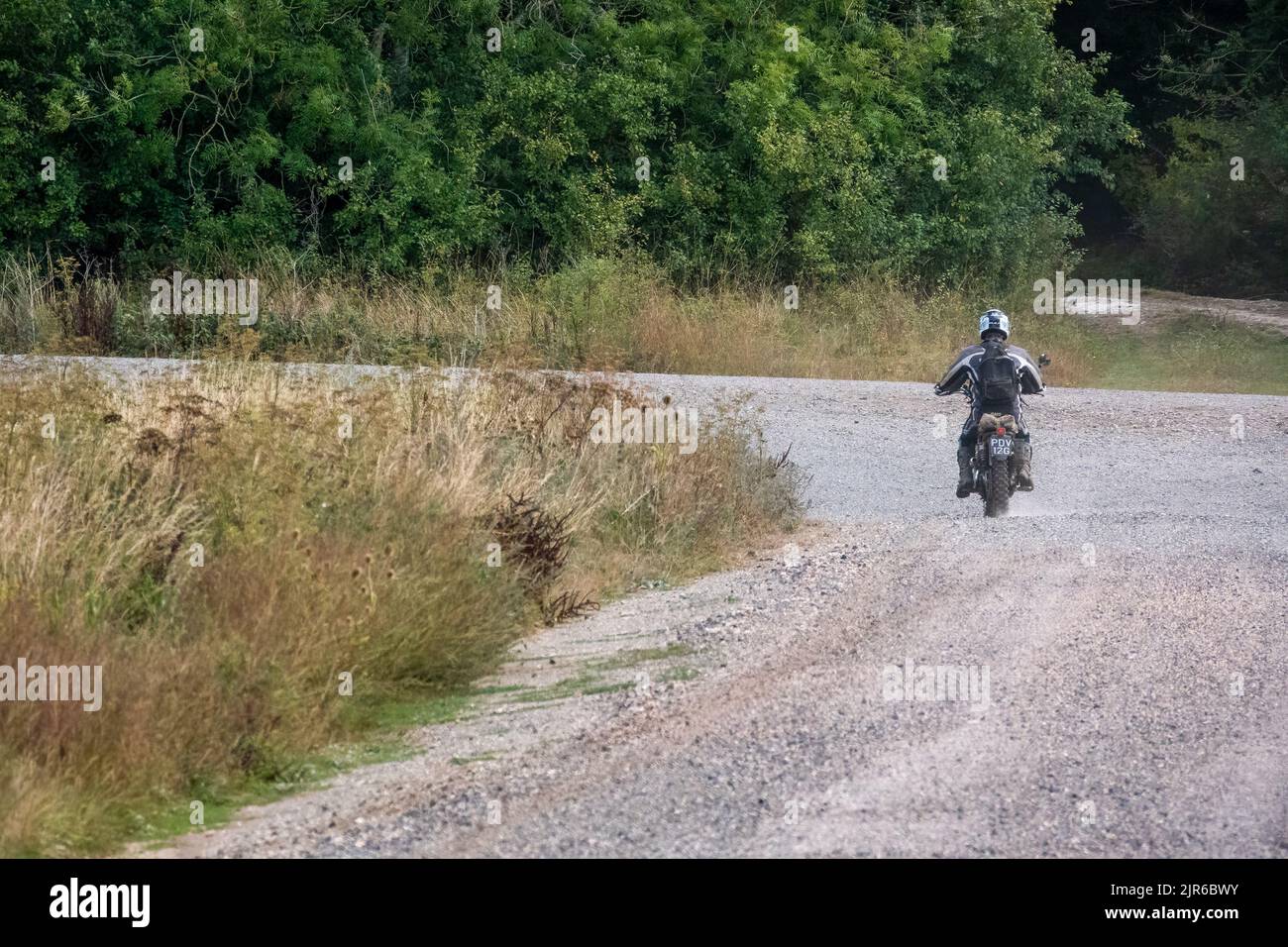 a motor cyclist (biker) riding their off-road motorbike along a dusty ...