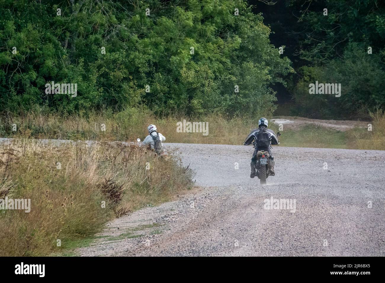 two motor cyclists (bikers) riding their off-road motorbikes along a ...