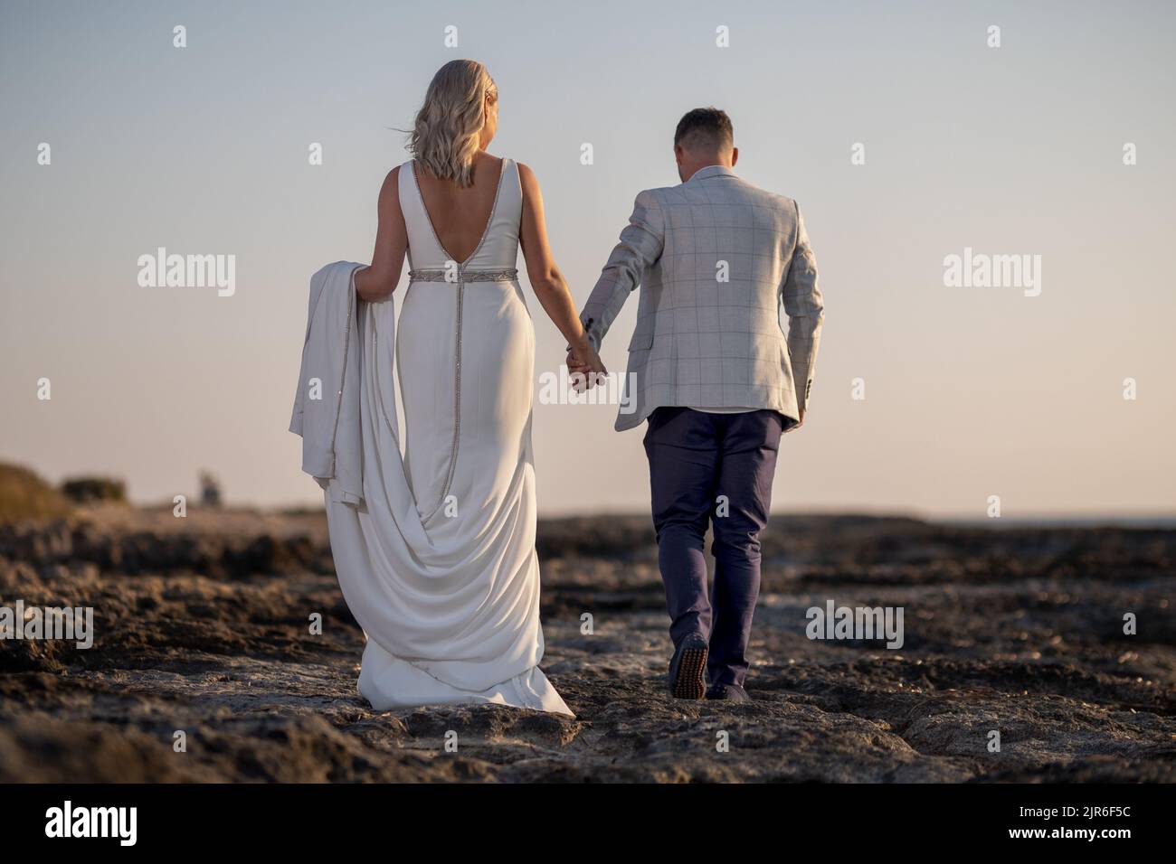 A back view of the bride and the groom walking and holding hands Stock ...
