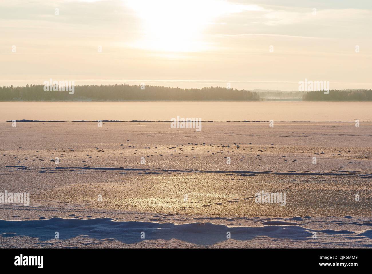 Sun shining above a frozen and snowy lake in Finland in the winter ...