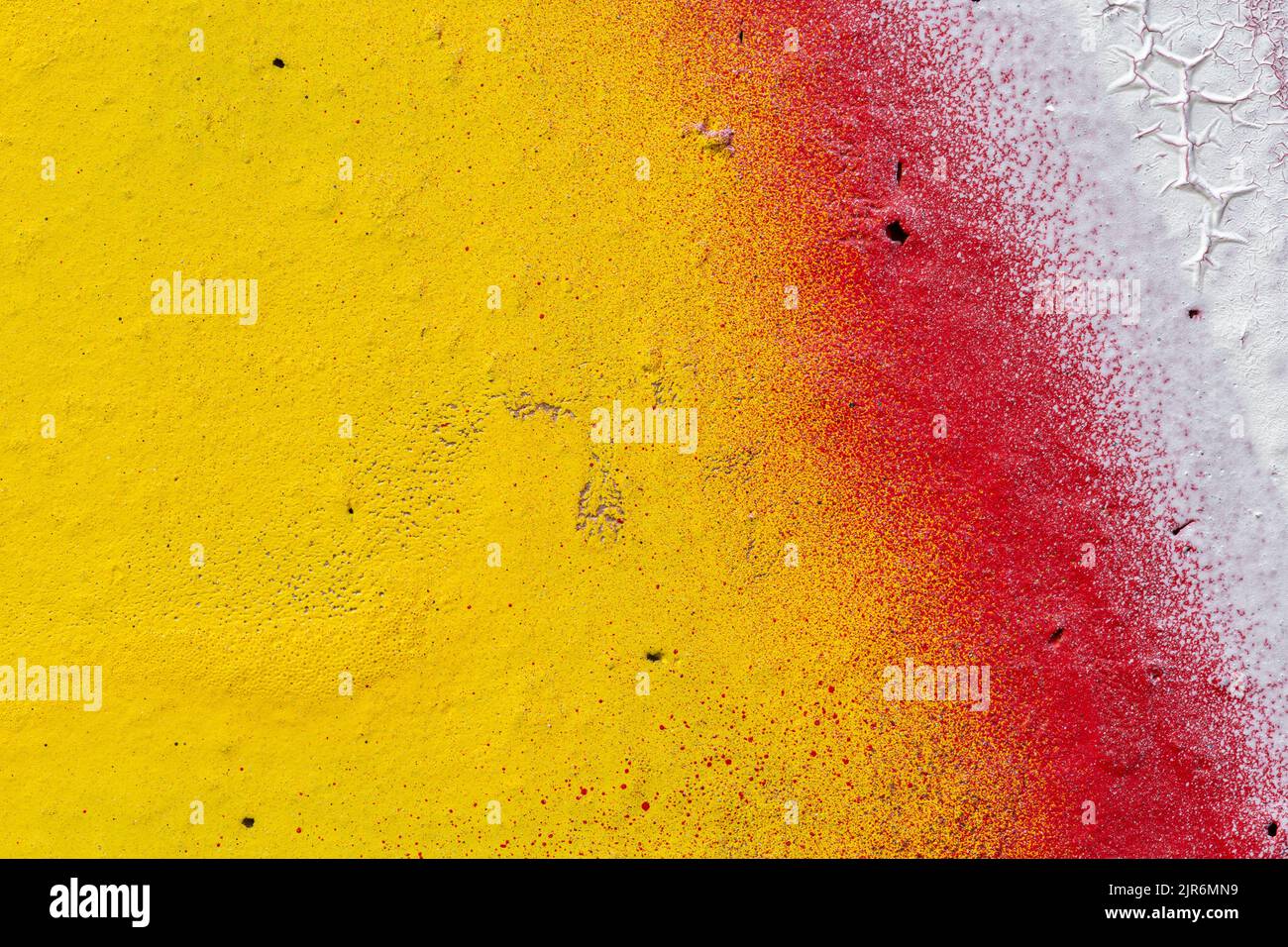 Macro close-up of a wall spray painted with yellow, red and white ...