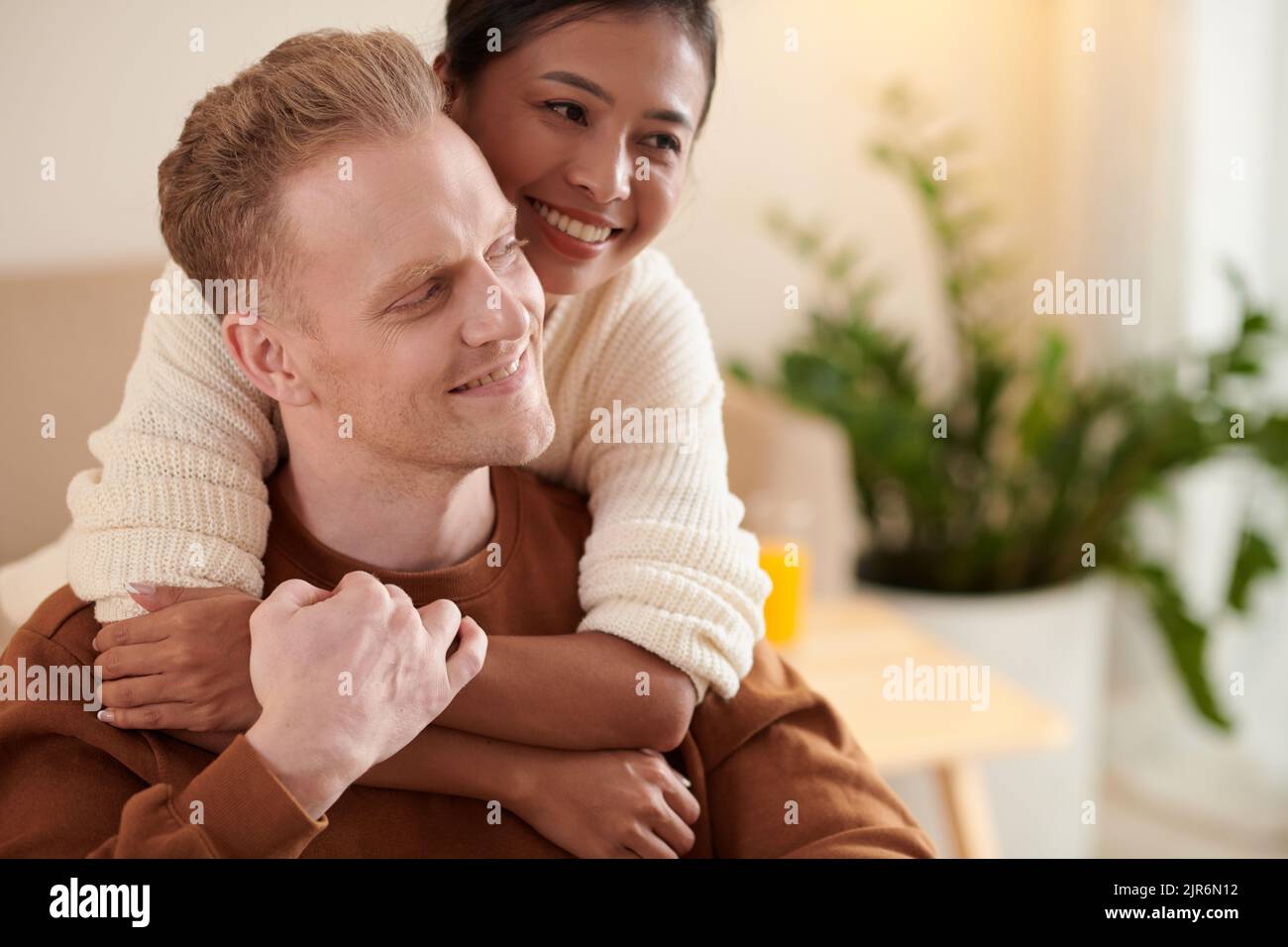 Smiling young Asian woman hugging her happy boyfriend from behind Stock Photo - Alamy