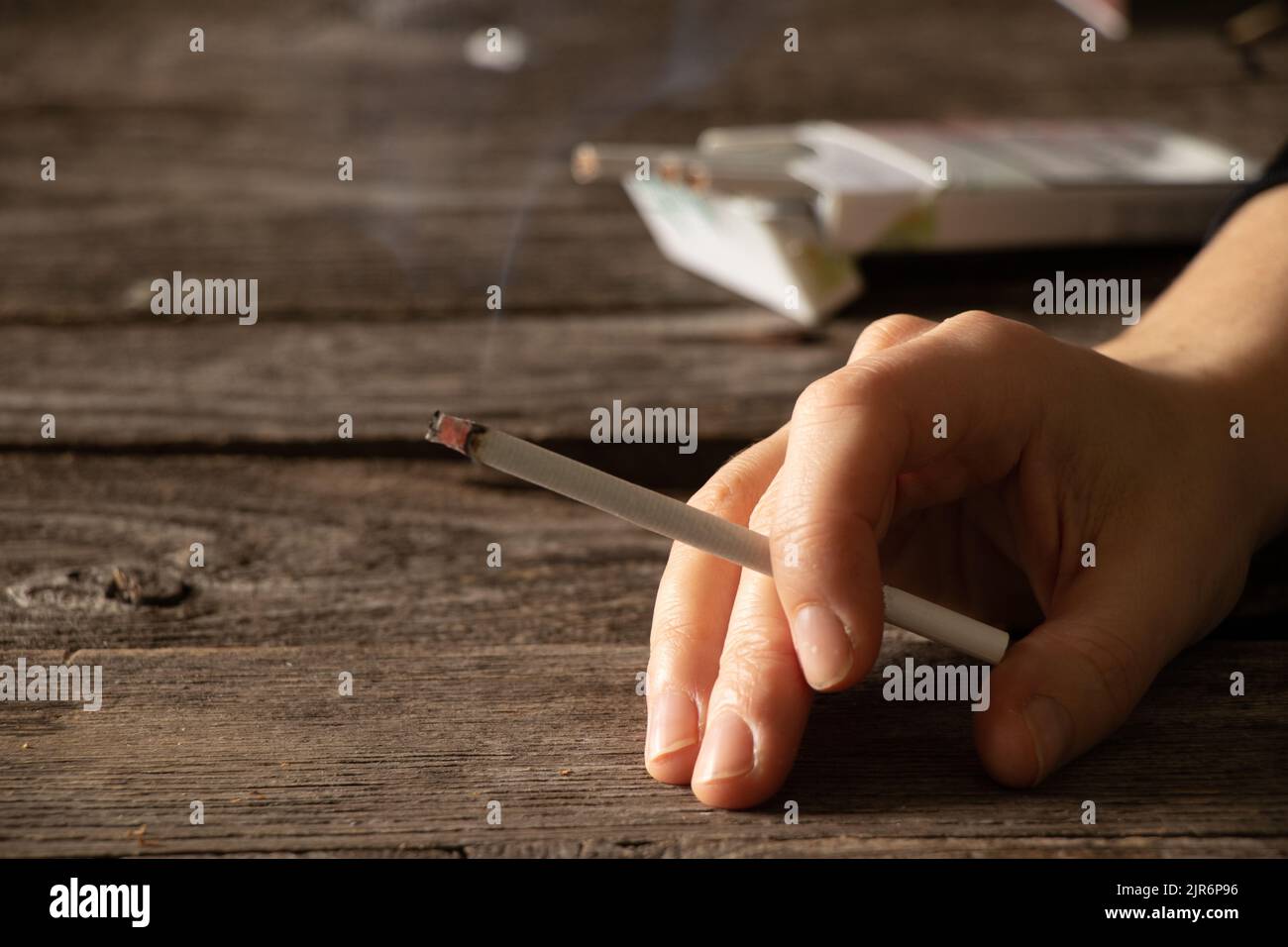 woman holding a cigarette at home at the table, smoking at home in the ...