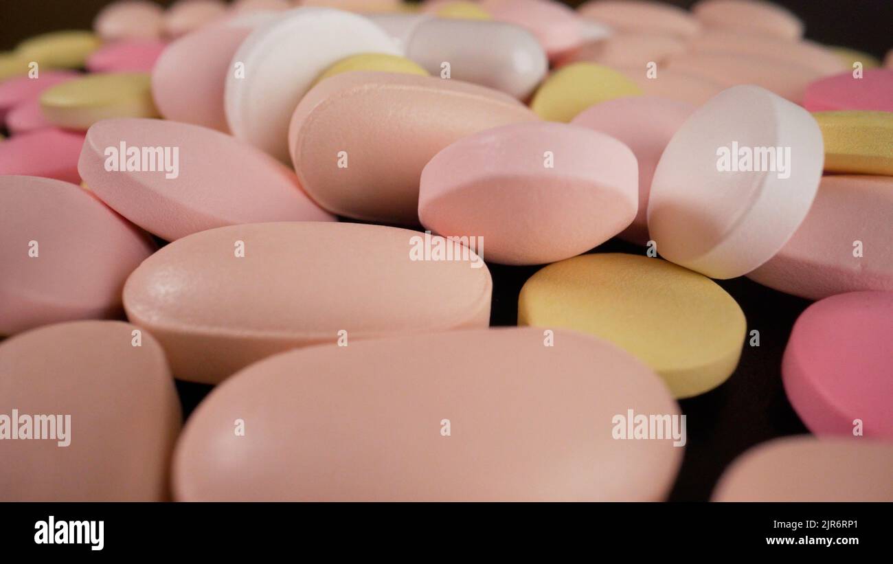 Multi-colored pills on a large black table. Colorful medical pills are ...