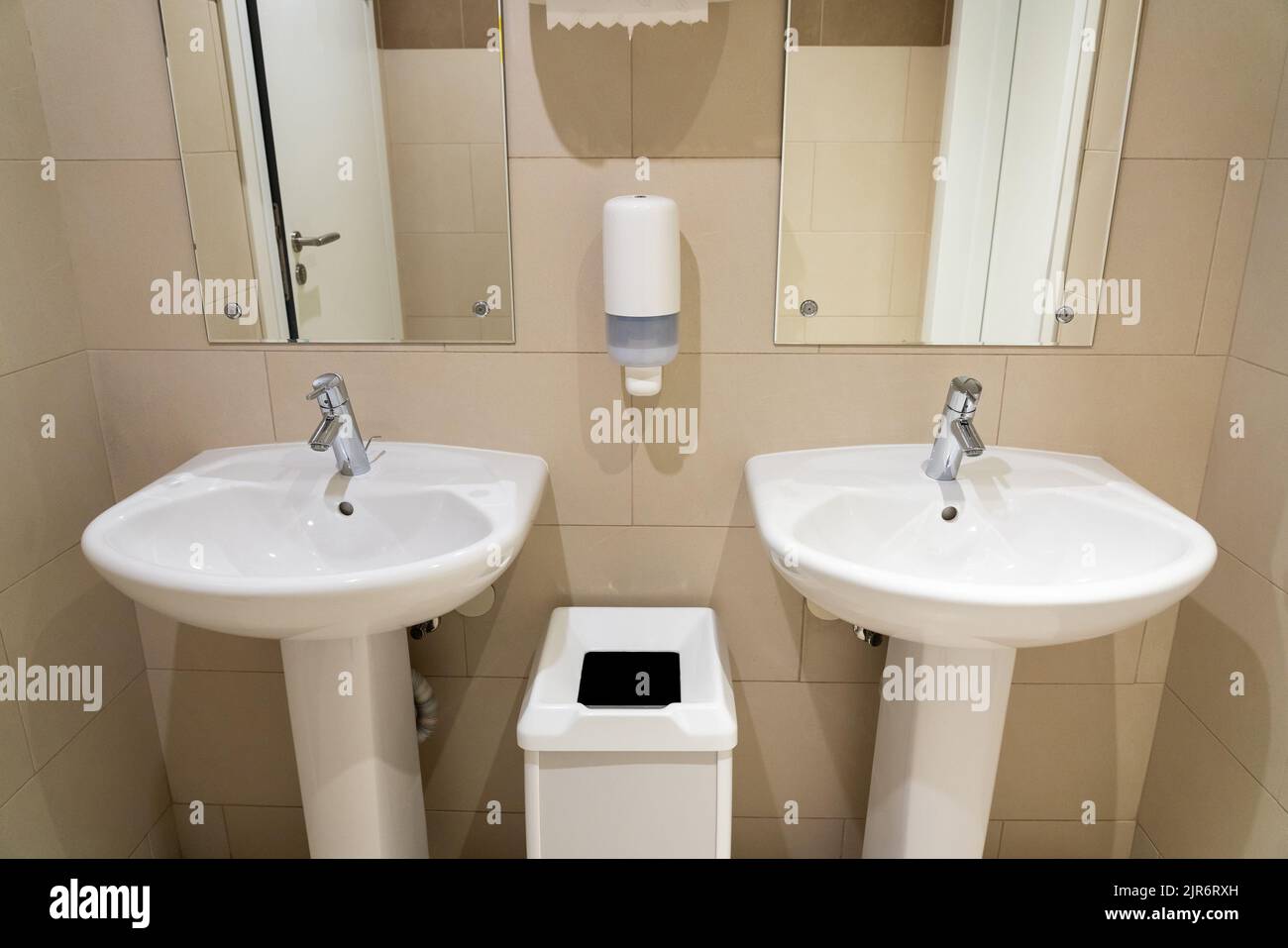 Ceramic sinks in a public toilet with a soap dish and a wastebasket ...