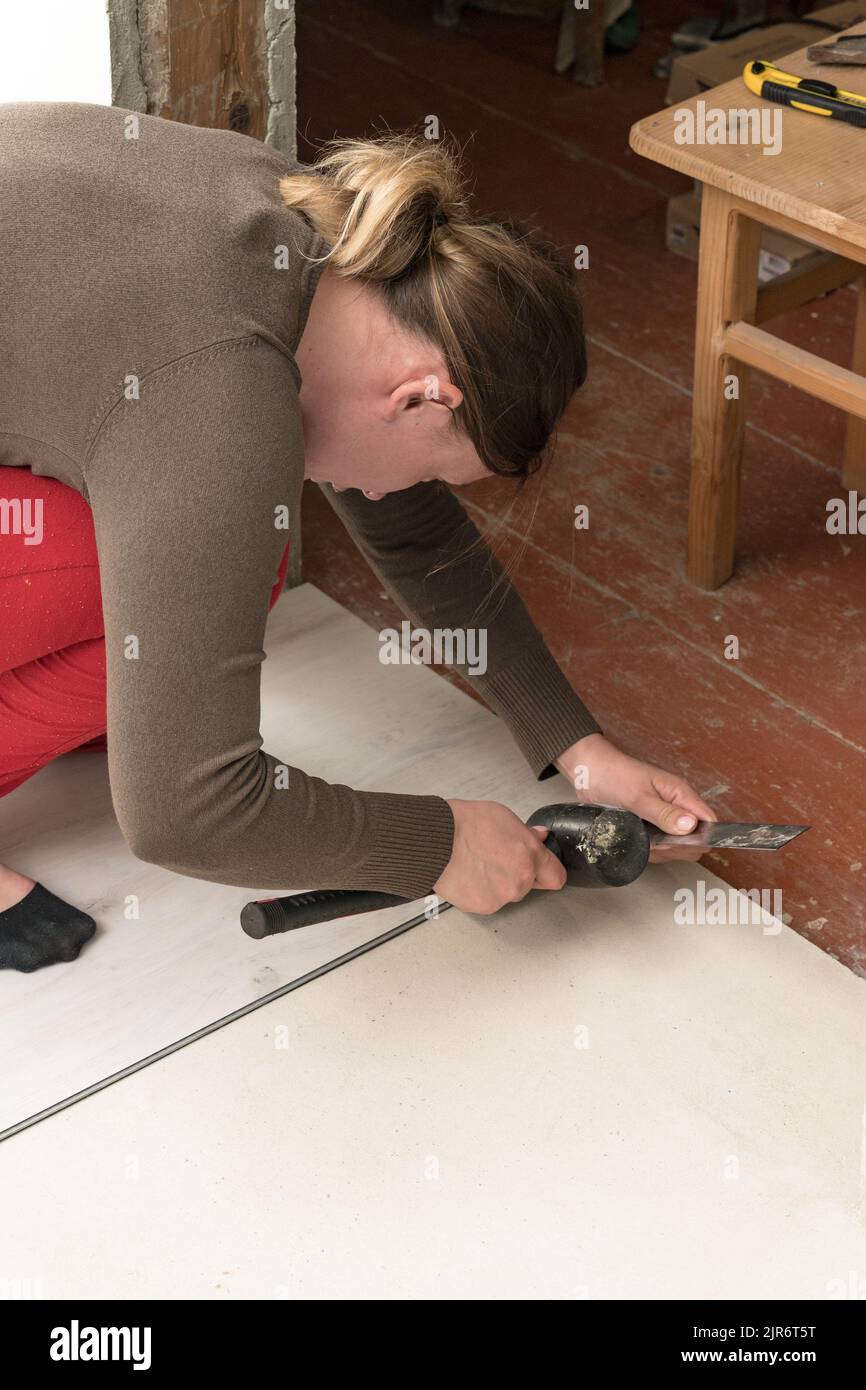 Woman installs quartz vinyl floor, installation on a flat surface ...