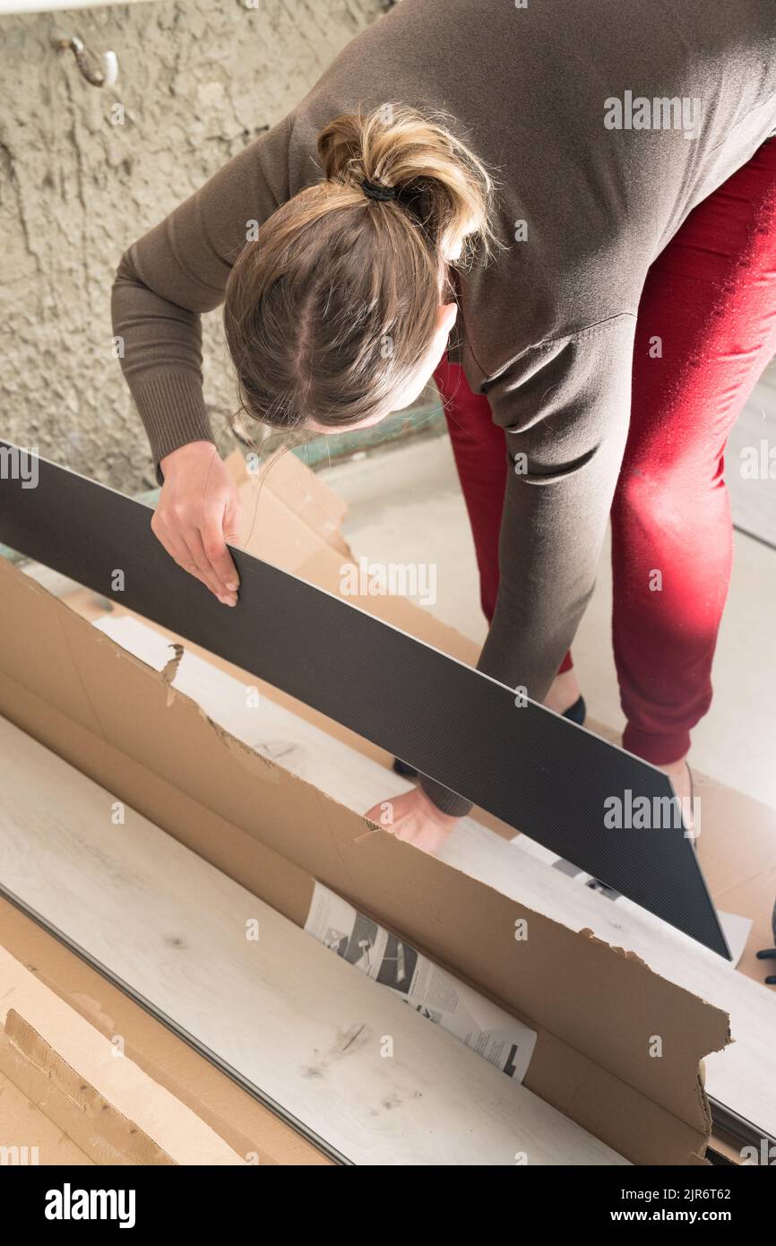 Woman pulls out of the box one board of quartz vinyl, repair work to ...
