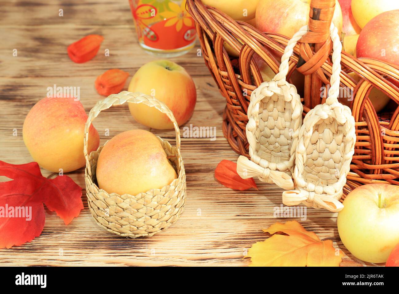 Red apples lie in wicker plate on wooden table. Ripe tasty apples for ...