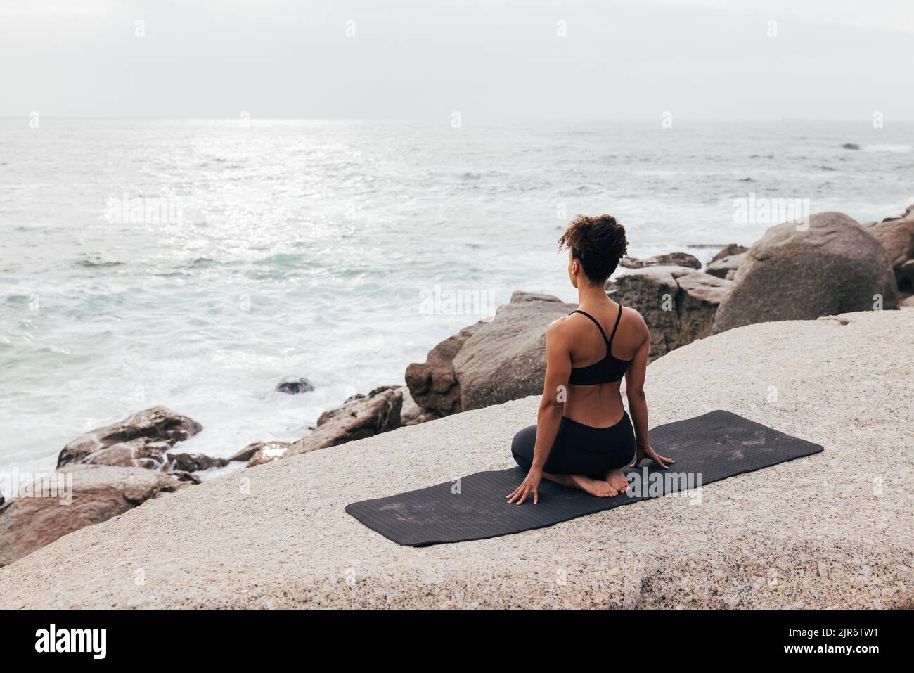 Back view of female in sportswear sitting in thunderbolt pose looking ...