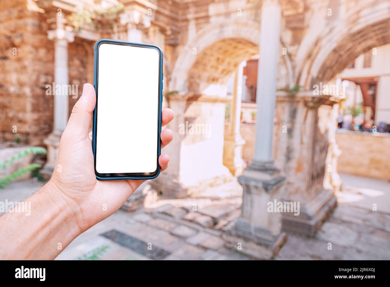 Hand with blank white screen of smartphone against background of ...
