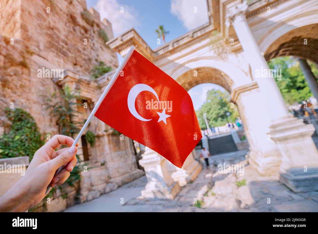Turkish Flag in hand and famous gate or Hadrian arch in Antalya. Travel ...