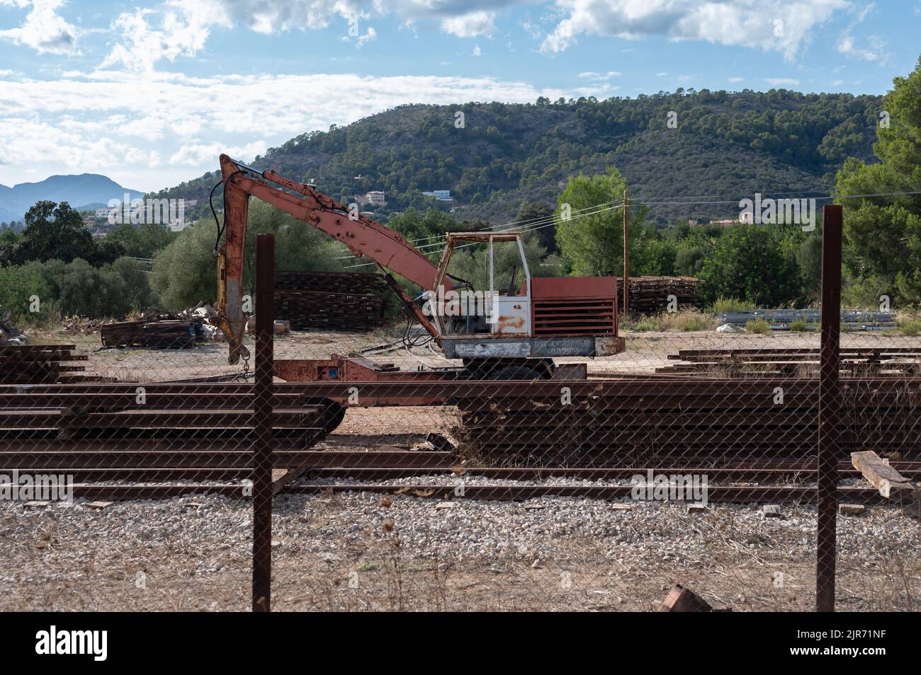 An old rusty, and abandoned excavator near the train tracks in a rural ...