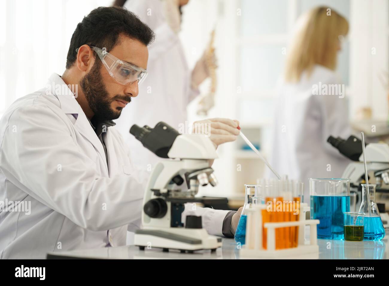 scientist doing research on plants holding a green solution in a test ...