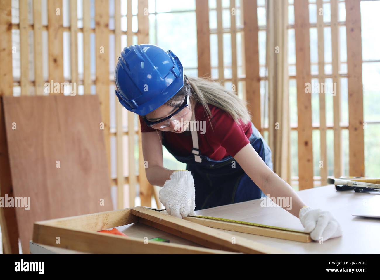 Side view portrait of modern female carpenter measuring wooden part ...