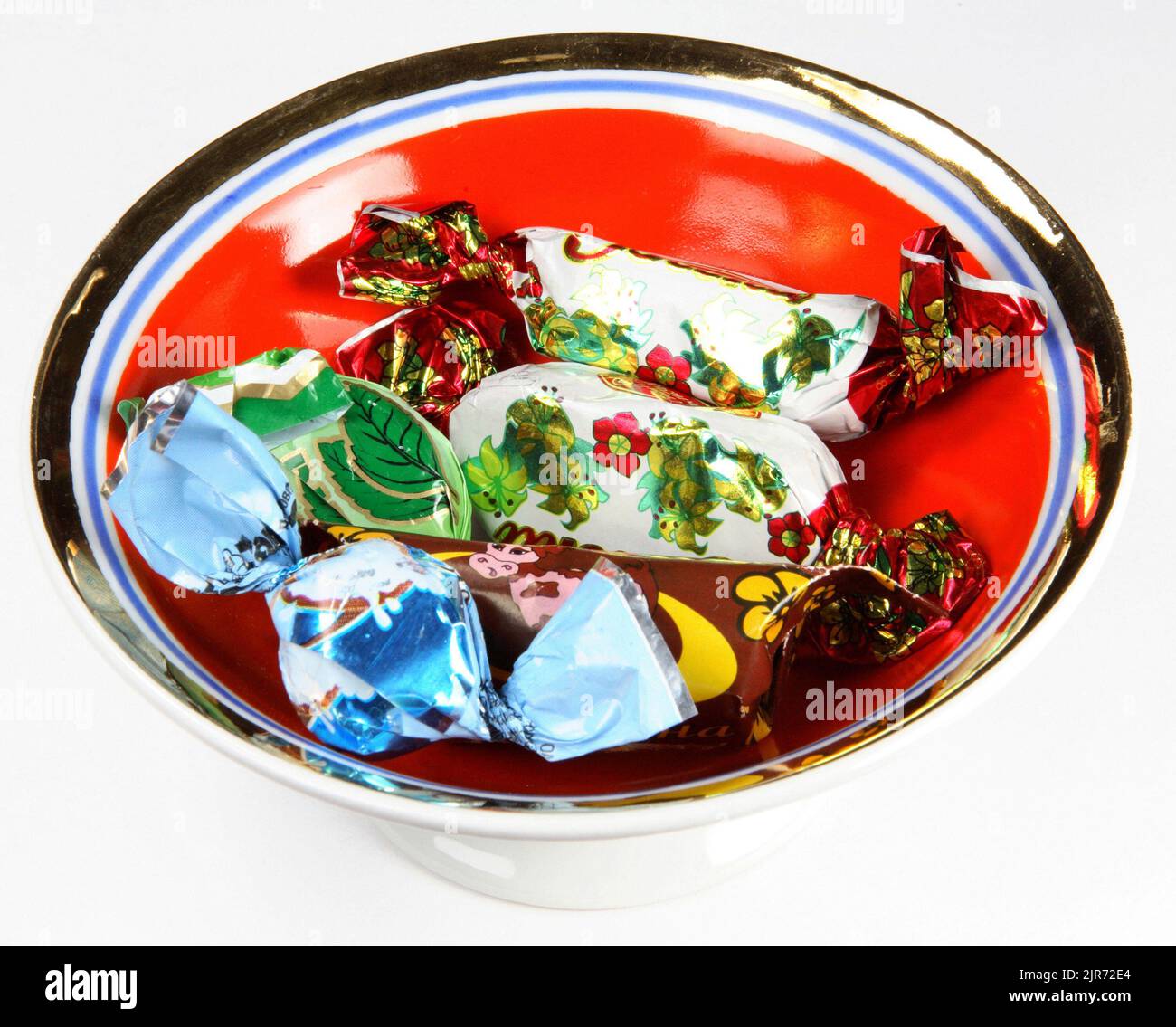 set of candies in sweet wrapper on red saucer Stock Photo - Alamy